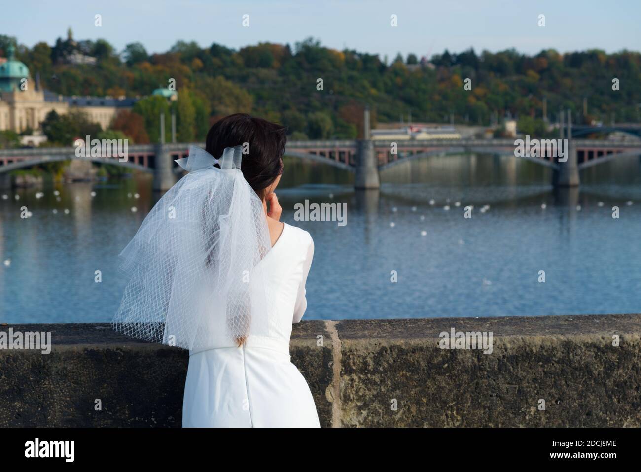 The bride admires Prague from Charles Bridge. Girl in a wedding dress ...