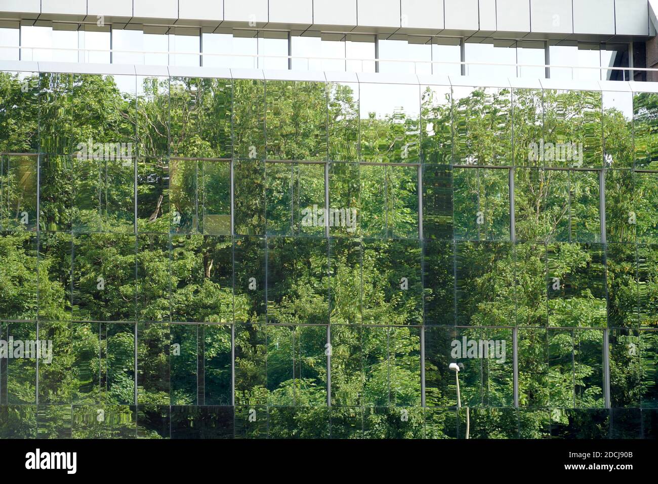 A cutout of a modern building with a glass facade. There are trees ...