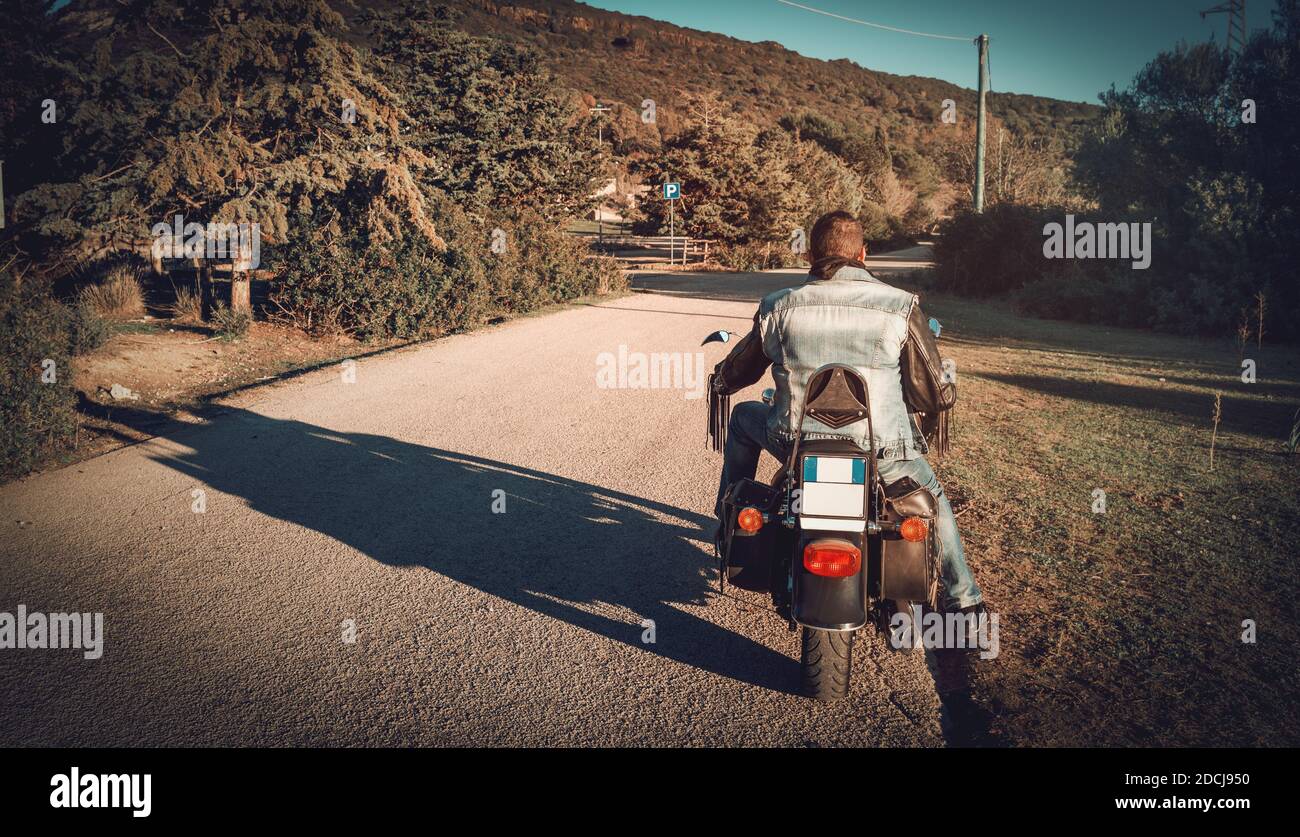 Biker on a classic motrocycle on a country road at sunset Stock Photo ...