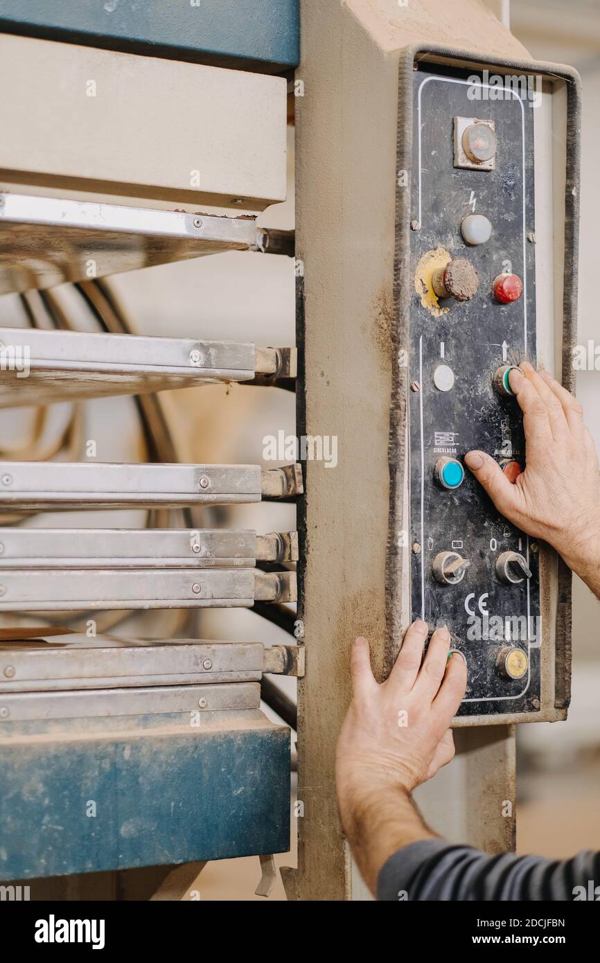 A vertical shot of a worker using colorful knobs and buttons on an ...