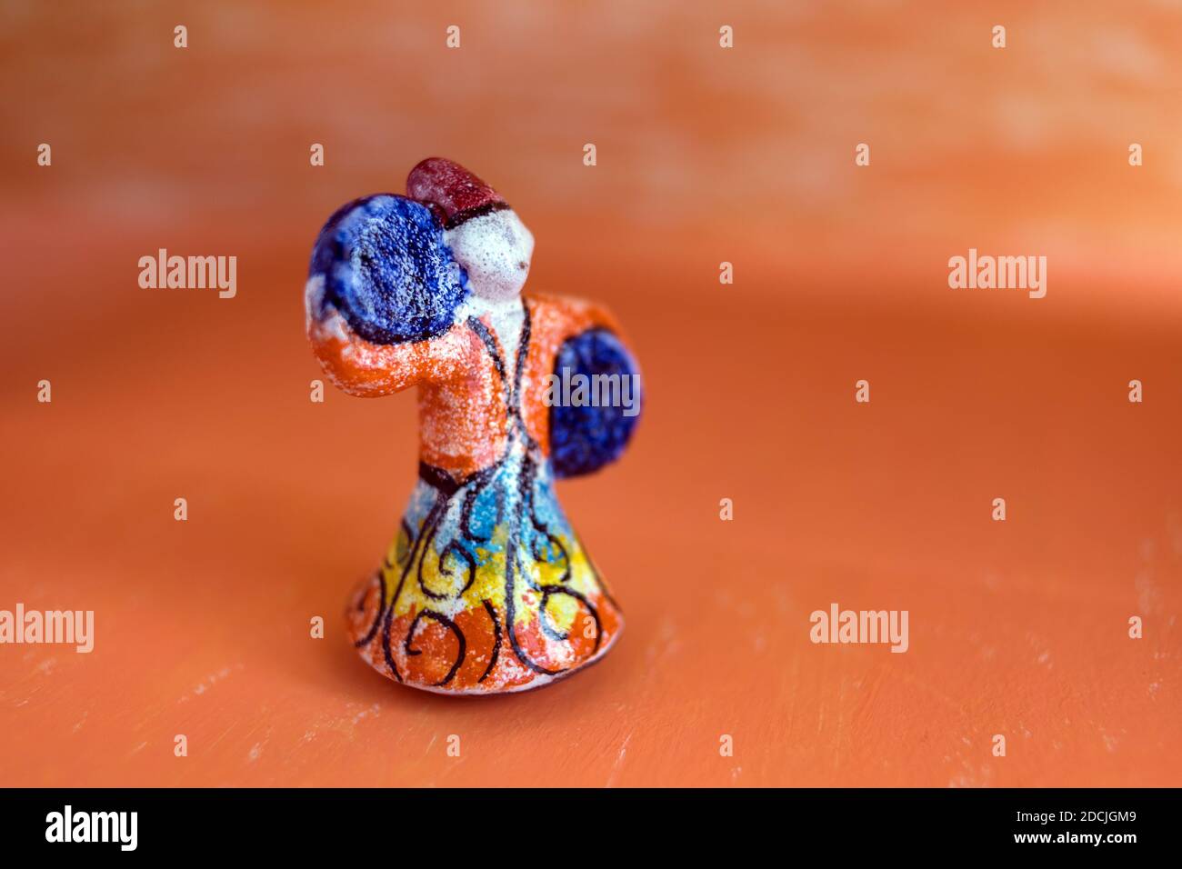 colored pottery doll of dancing dervish on orange background for wall ...