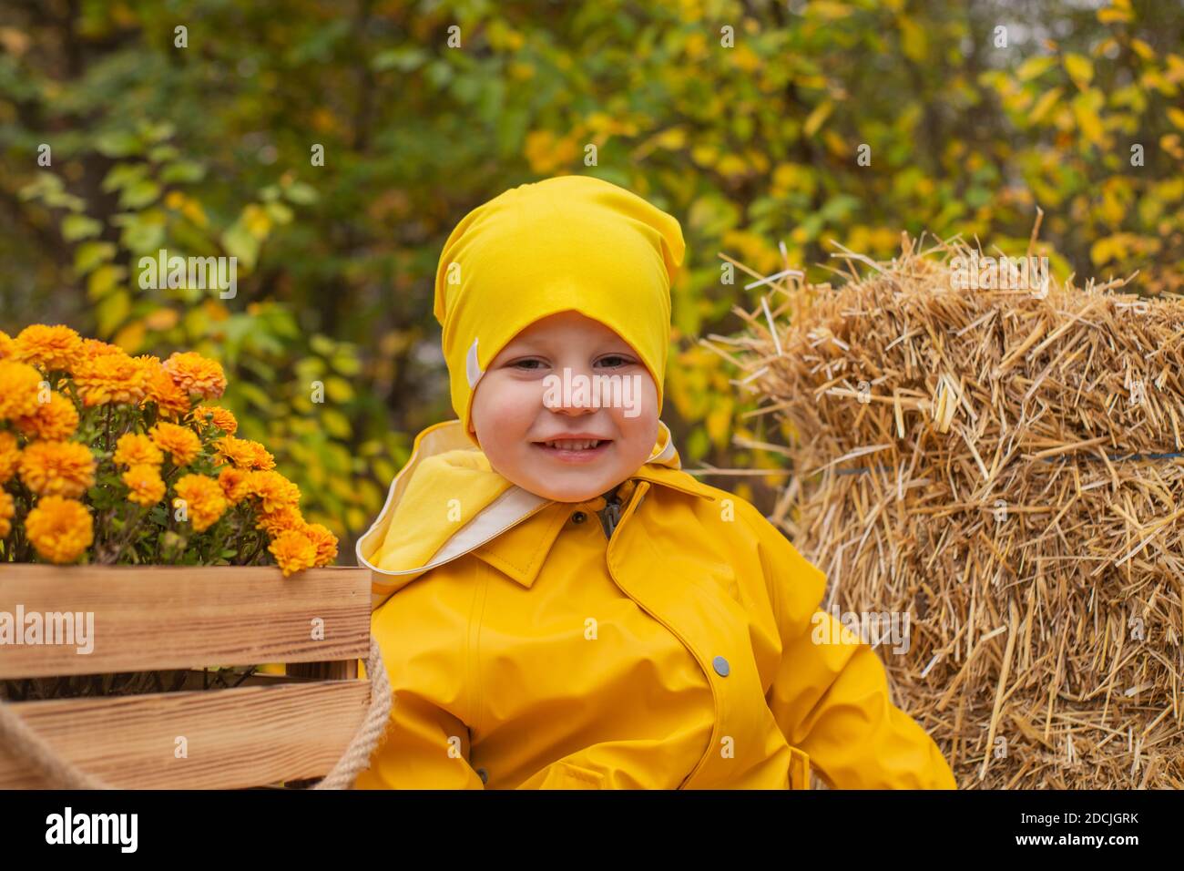 cute beautiful prescholer boy in an orange pants, raincoat, hat, rubber ...