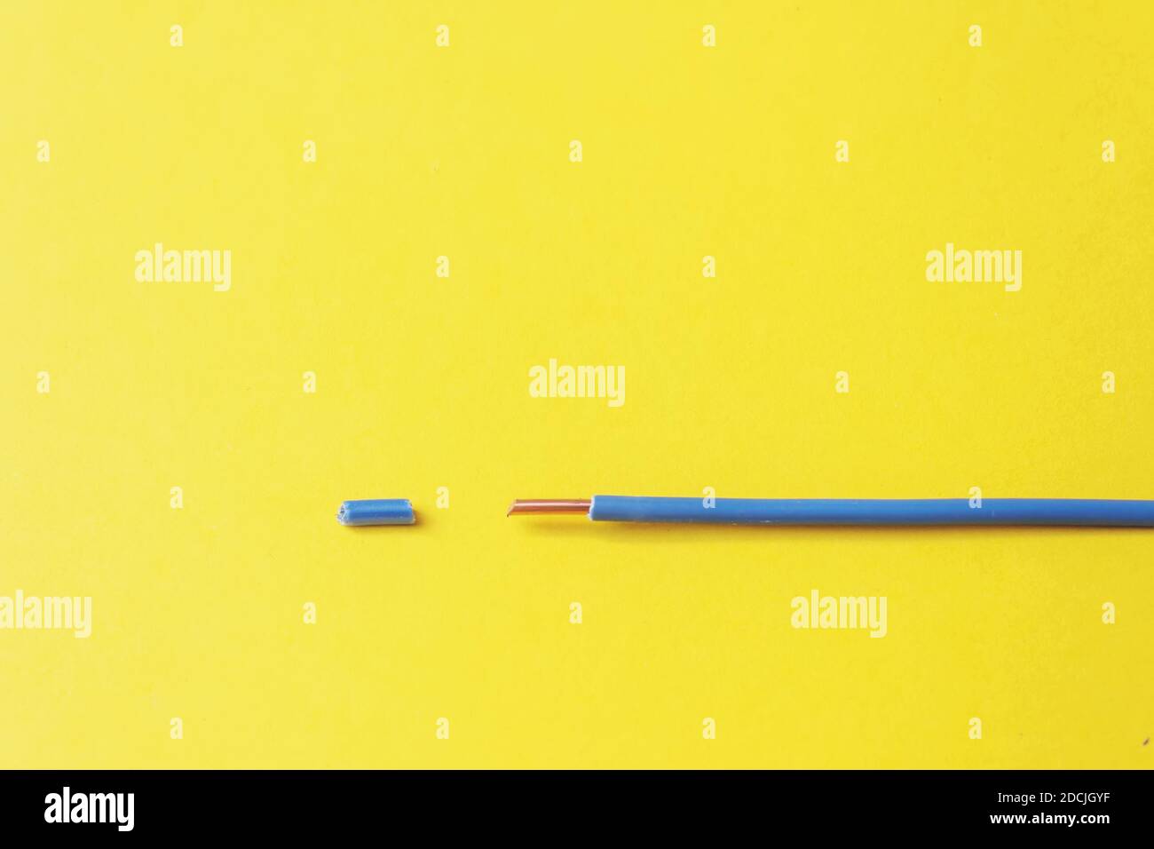 Blue electrical wire stripped of insulation on one side on a yellow ...