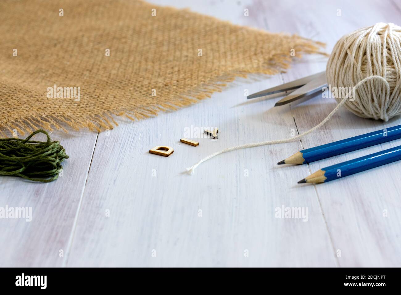 Wood letters of DIY, do it yourself with pencils, scissors, threads and ...