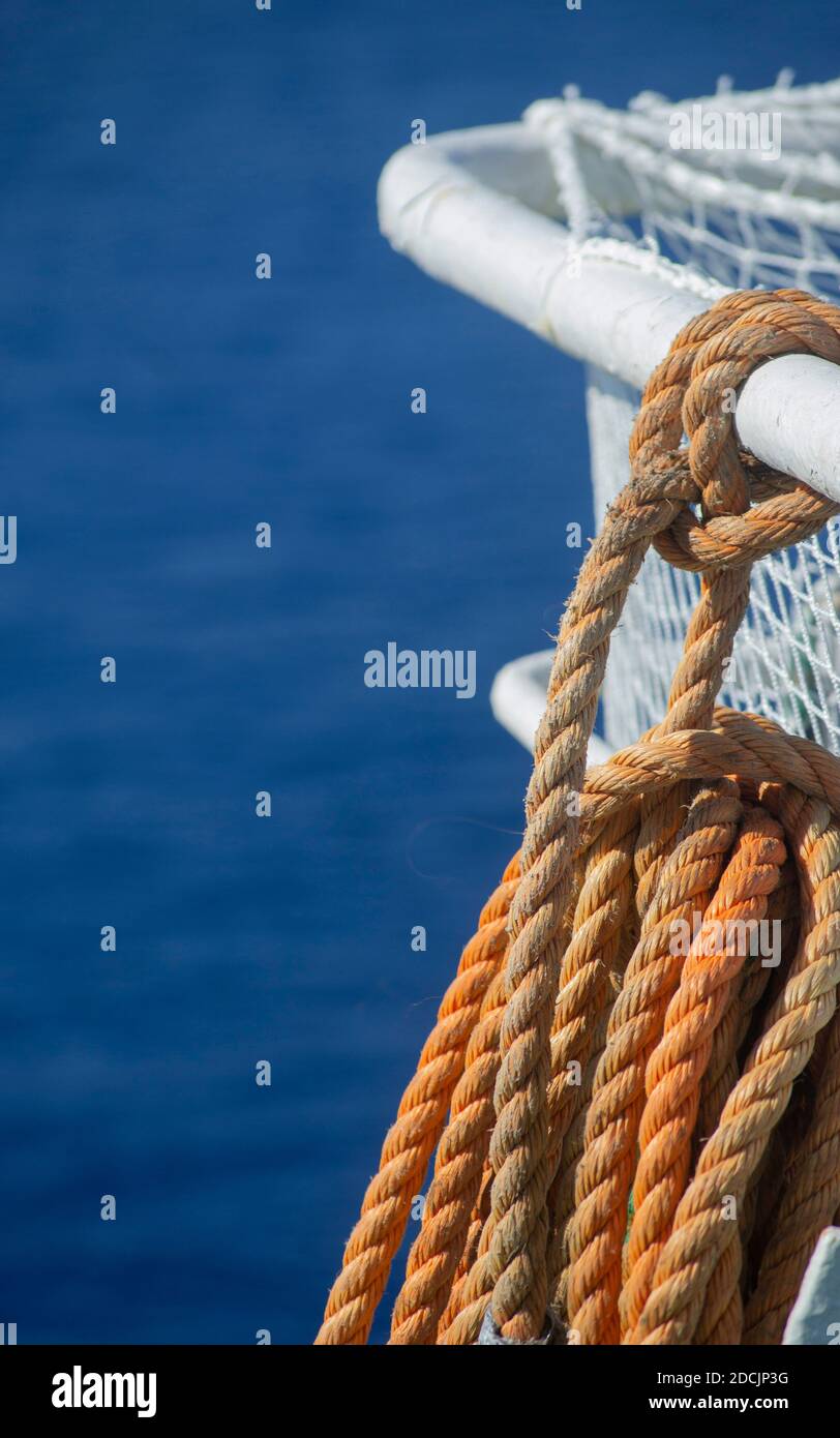 Colorful rope knot on the handrail of a ship in beautiful moody sunset ...