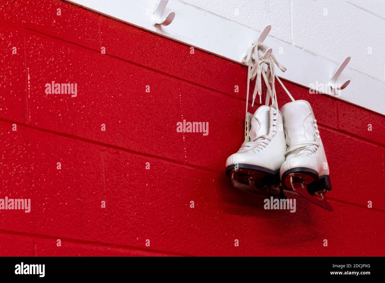 Figure skates hanging in locker room over red background with copy ...