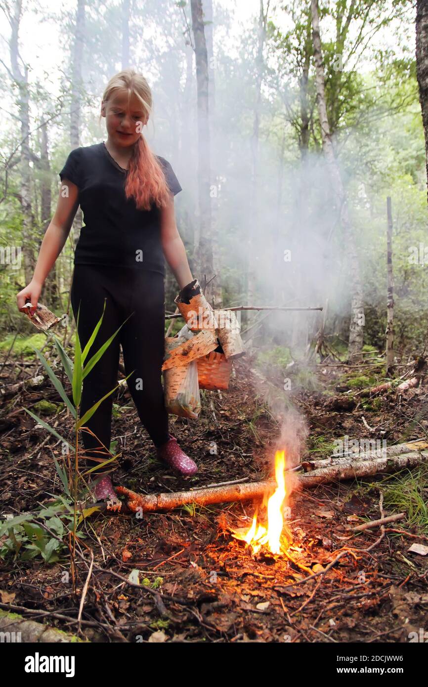 Teenager girl make a fire in the wild forest in countryside Stock Photo ...