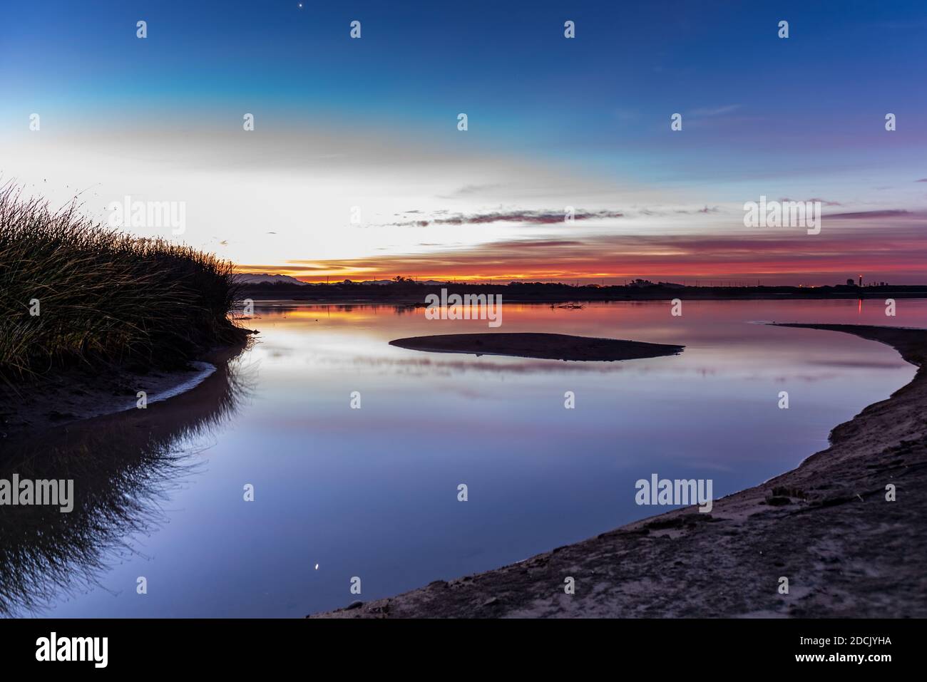 Estuary water surface reflects the golden sky with sand bar island ...