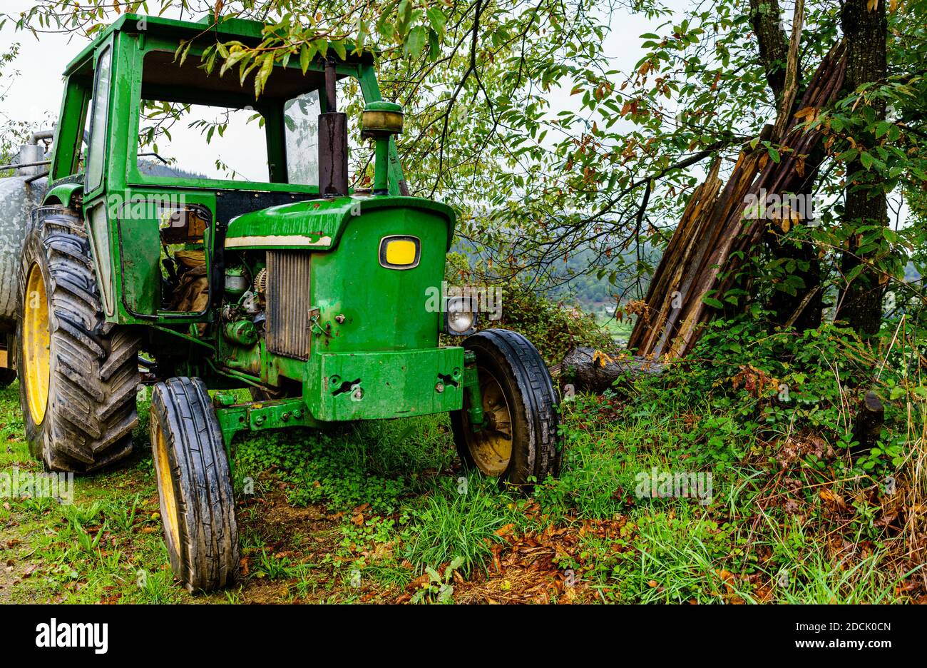 green tractor with green grass, wood stick, branches and tree Stock ...