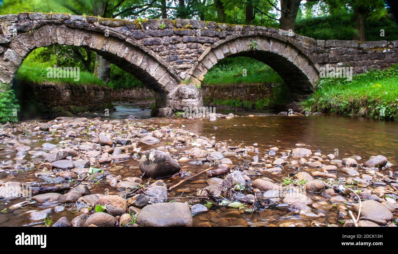 The Wycoller Beck straim flows under a traditional stone pack-horse ...