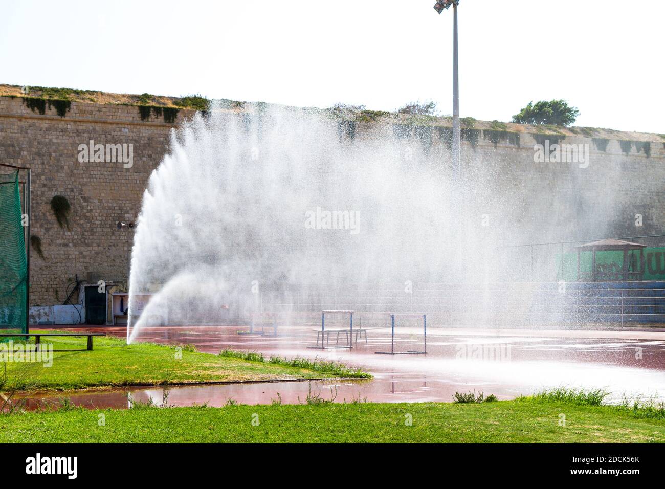 Sprinkler watering the grass of a public local sports training stadium ...