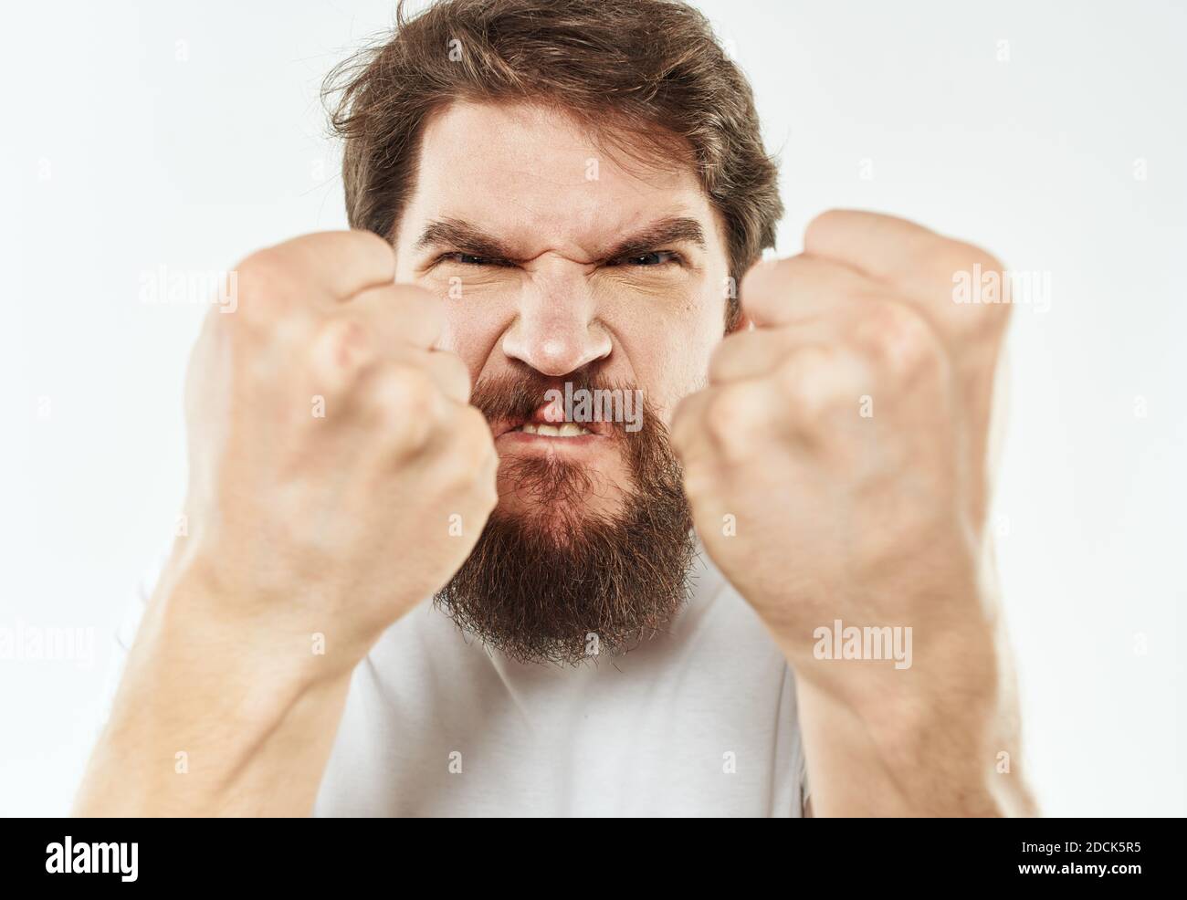 Angry man in a white t-shirt shows a fist gesturing with his hands to ...