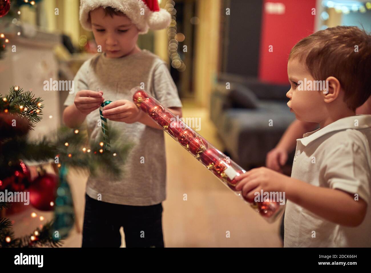 Children playing while decorating a Christmas tree in a holiday ...