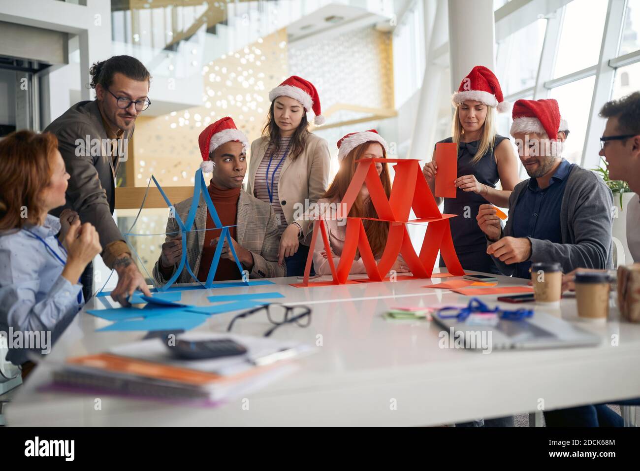 colleagues in bright office having fun for christmas, building paper ...