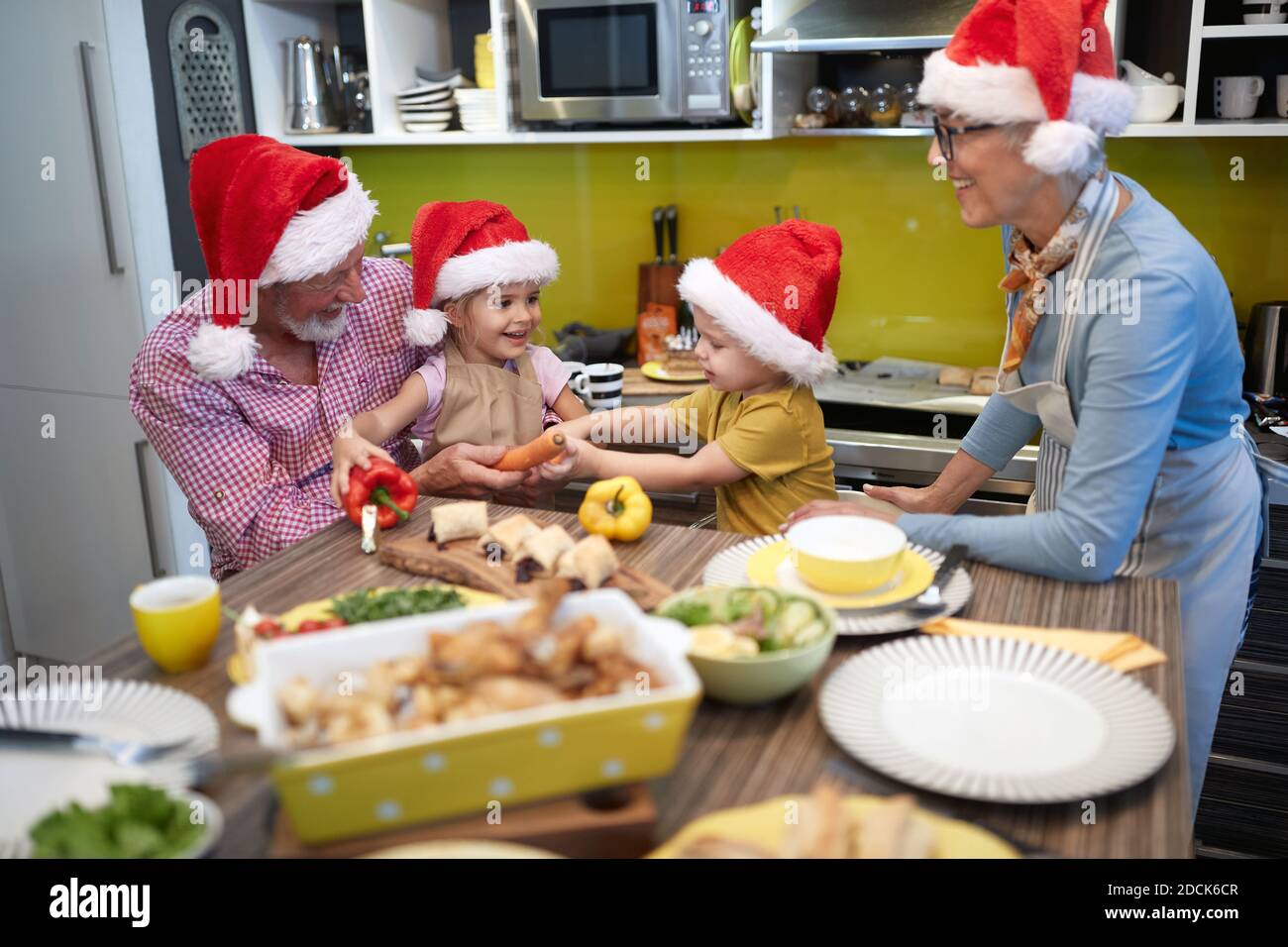 Grandpa, grandma and grandchildren preparing Xmas meal in the kitchen ...