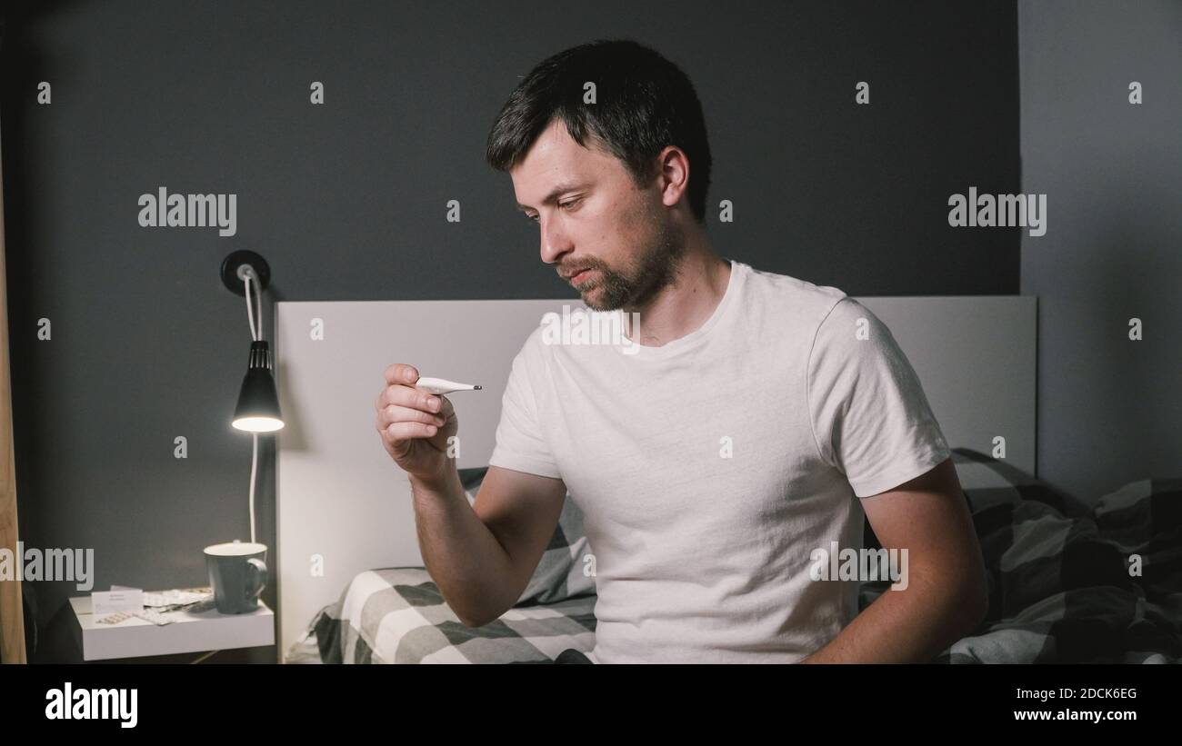 Young man ill with flu at home. Guy having flu. Diseased male sitting ...