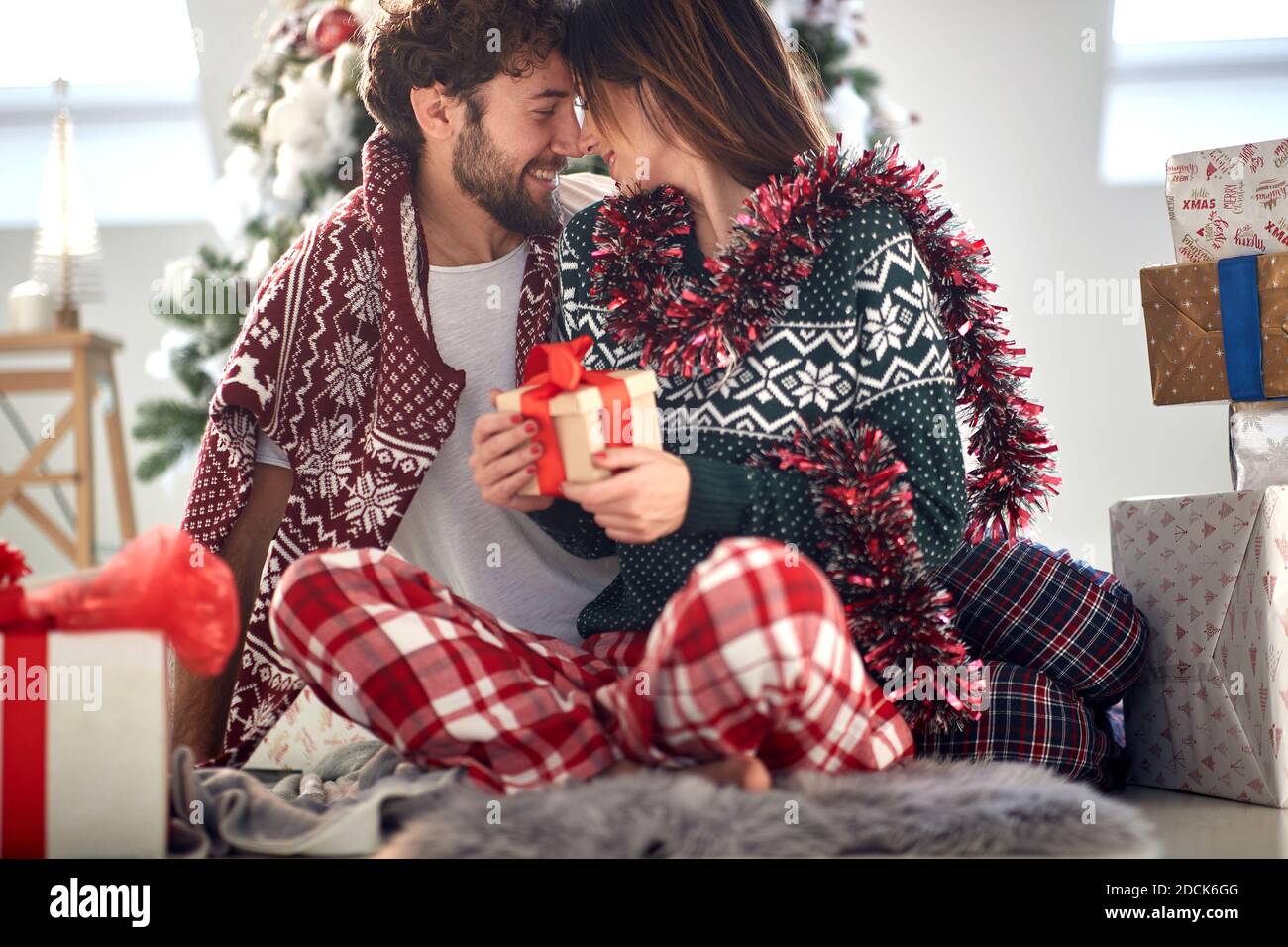 A young couple in love has moments of closeness giving Xmas presents at ...