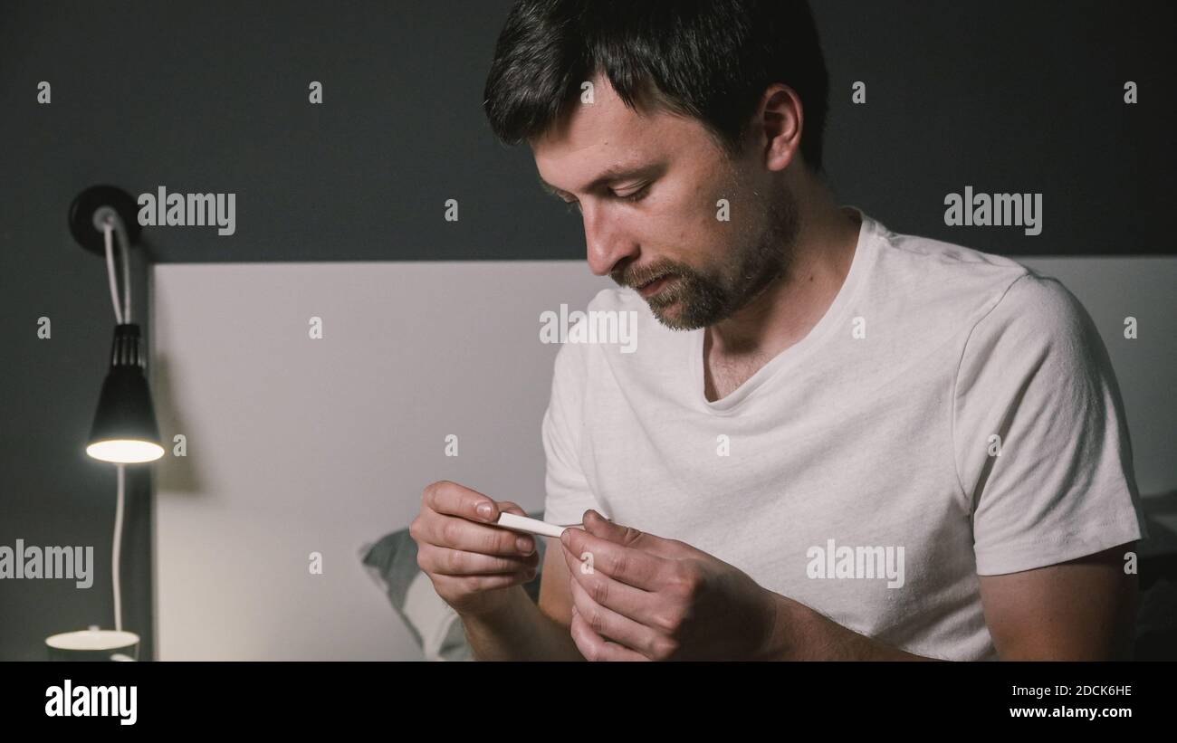 Sick man in bed measuring temperature feeling fever. High temperature ...