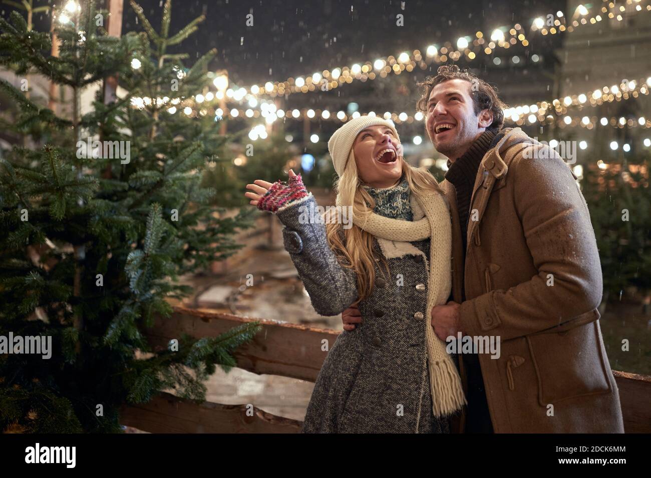 A young couple in love excited about snowfall in a magical night in the ...
