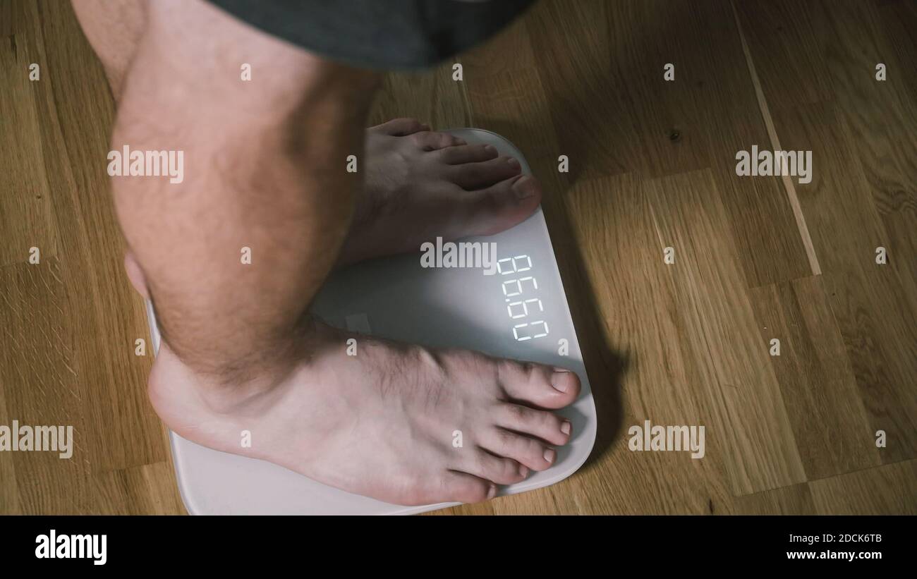 Man step on digital glass scales to check weight. Male weighting on ...