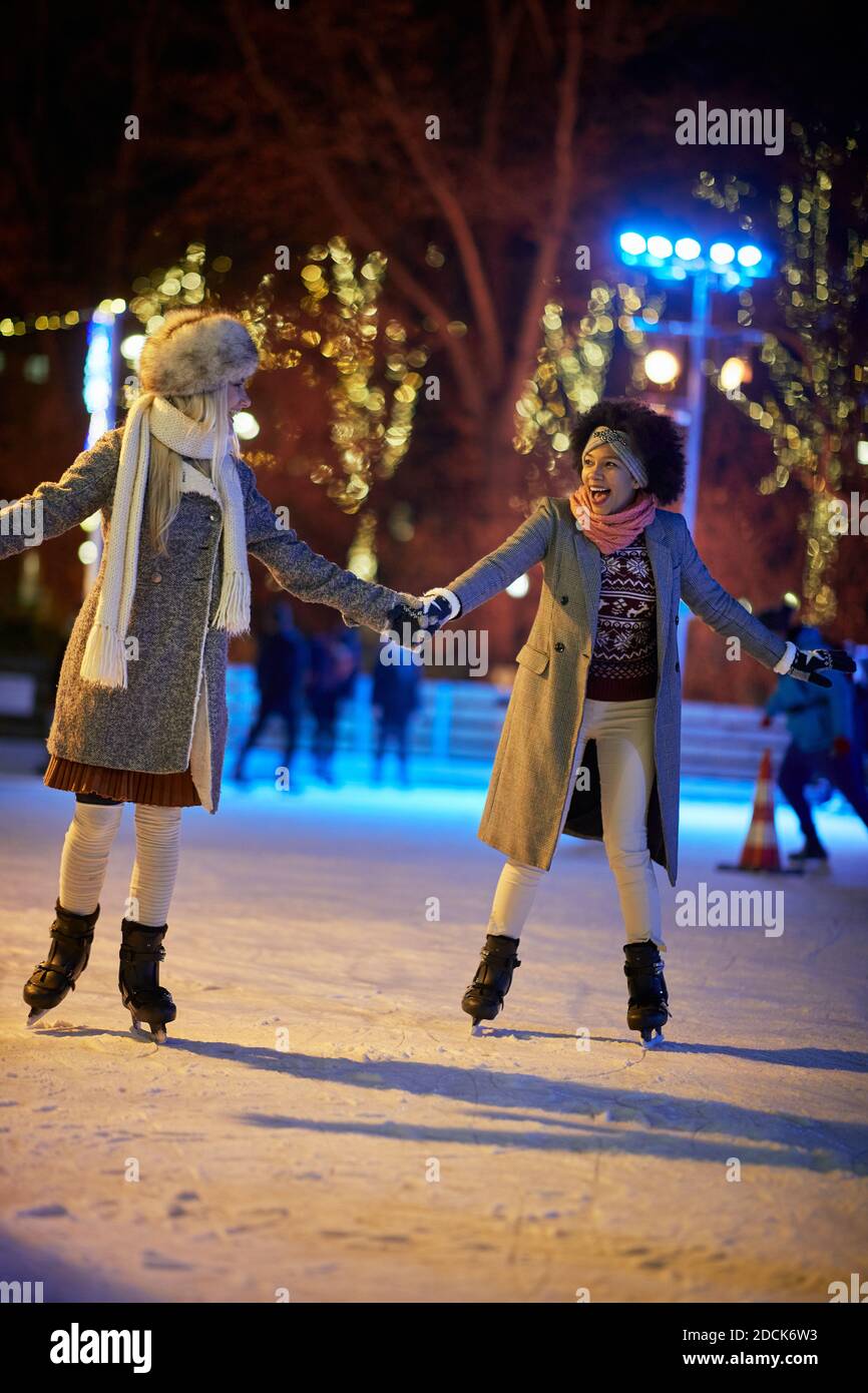 Female friends skating together at ice rink on a beautiful magical ...