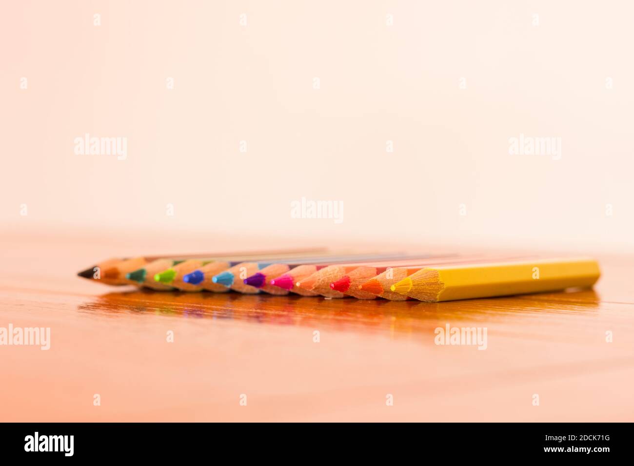 Close up on a diagonal row of twelve color pencils aligned on brown and ...