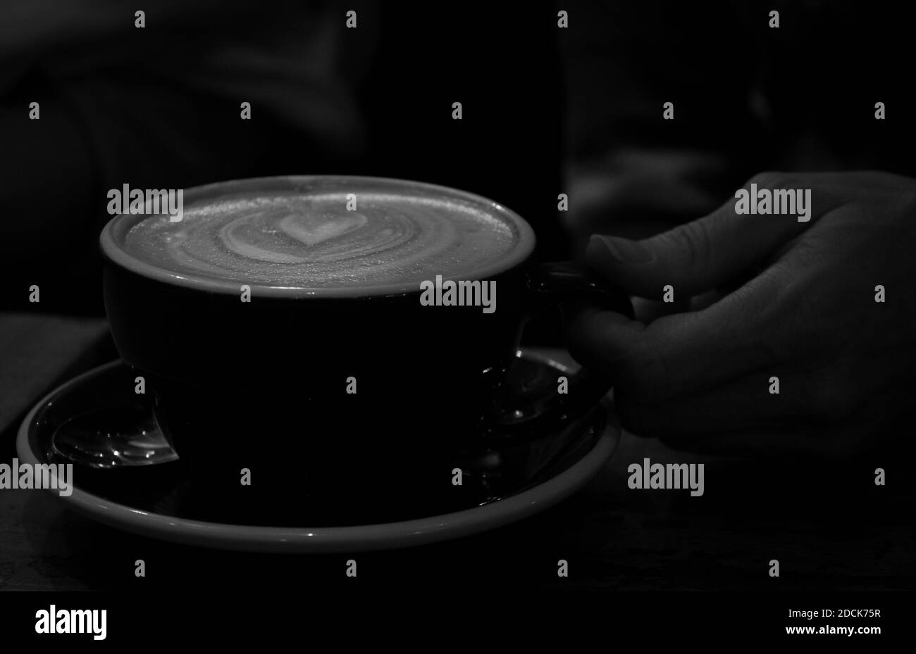 Hand of woman grabs cup of cappuccino coffee with heart leaf shaped ...