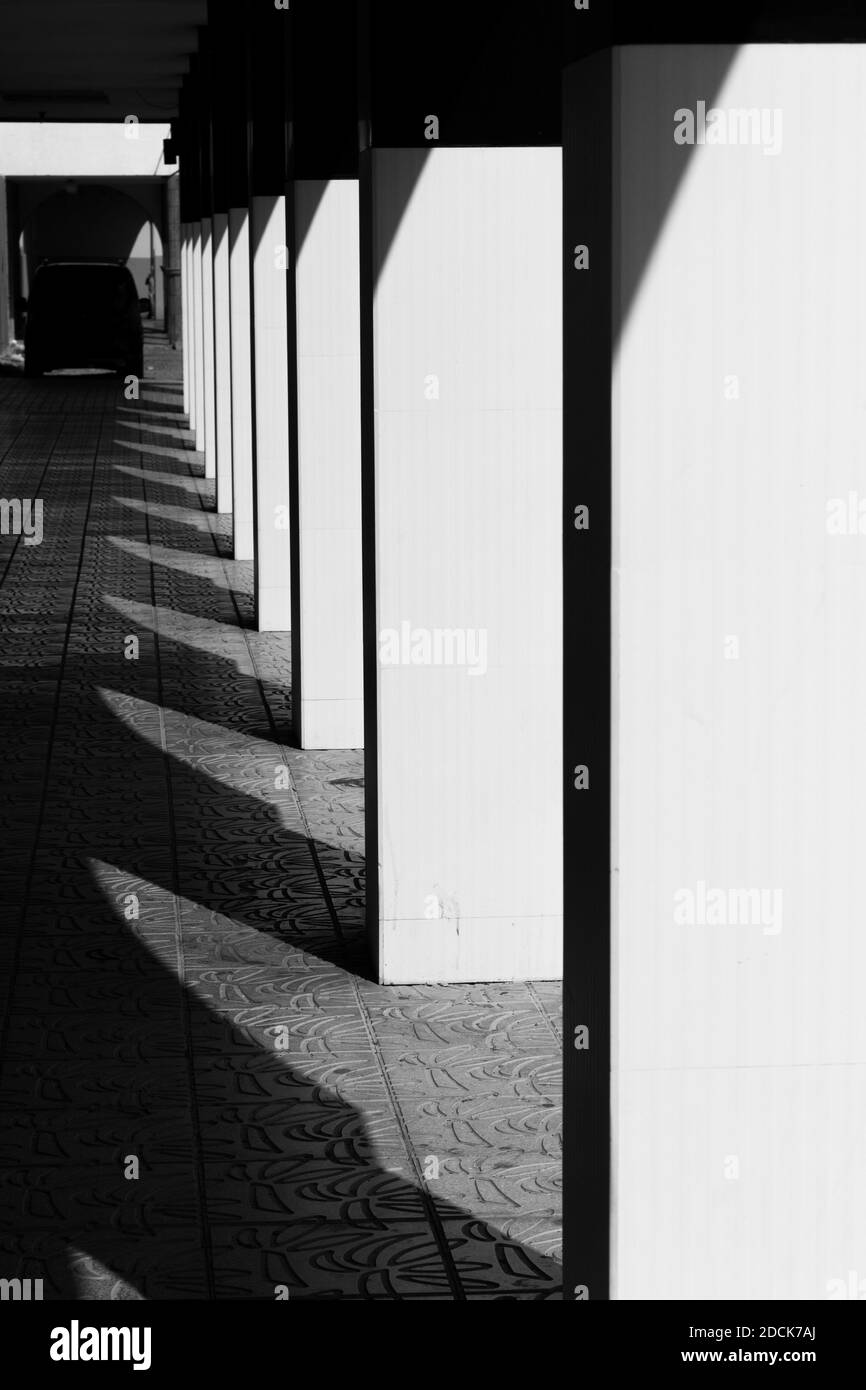 Row of columns with high contrast shadows on street building. Vertical ...