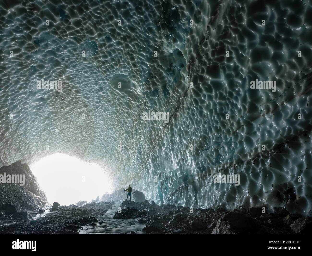 Mountaineer in the ice chapel with meltwater stream, ice field at the ...