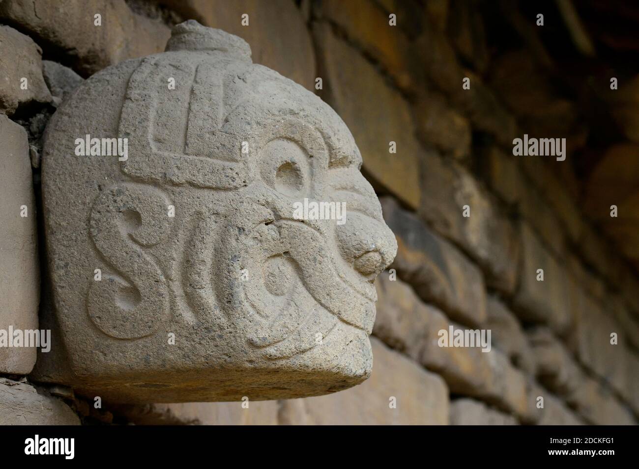 Stone head, half man half cat, on a wall of the ruins of Chavin de ...