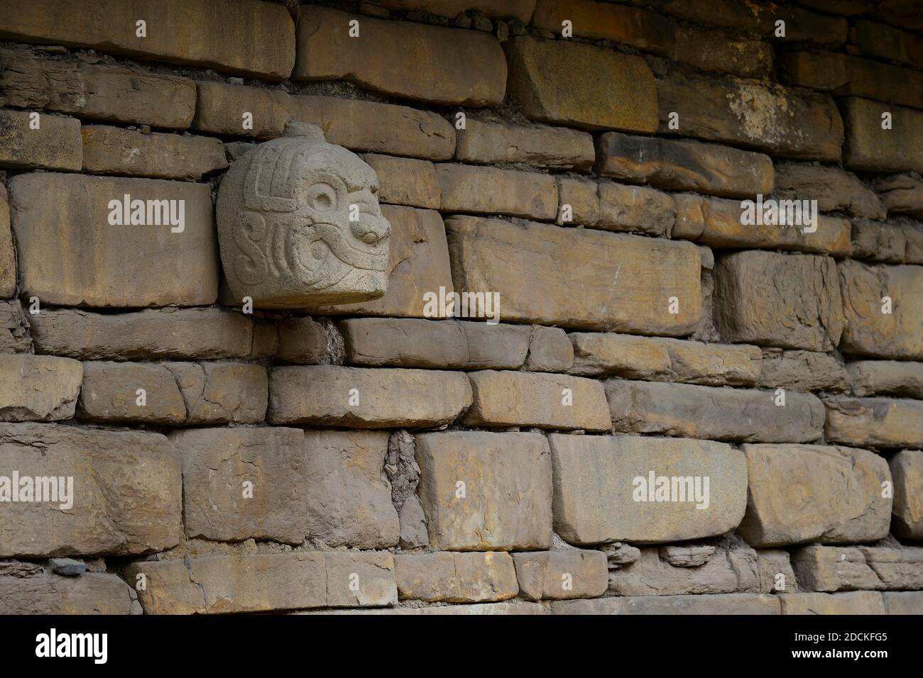 Stone head, half man half cat, on a wall of the ruins of Chavin de ...