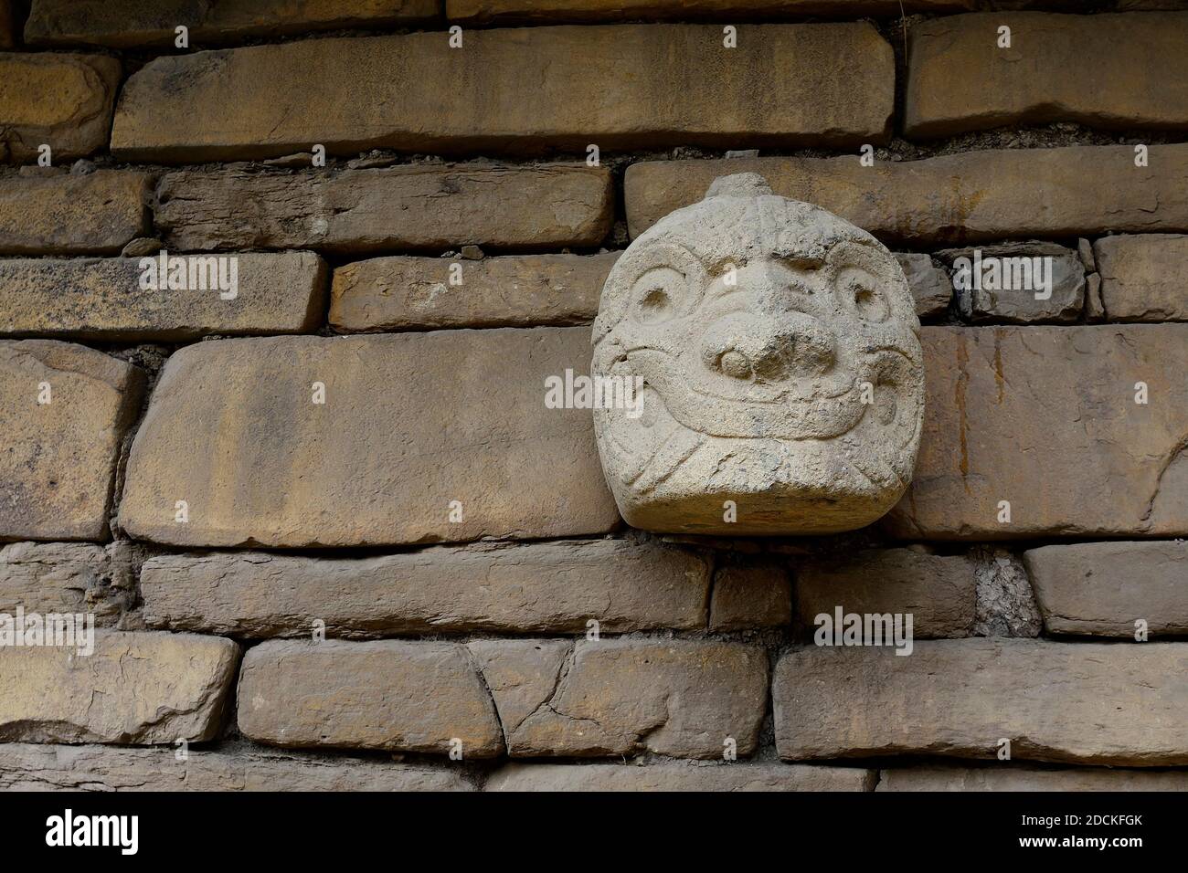 Stone head, half man half cat, on a wall of the ruins of Chavin de ...