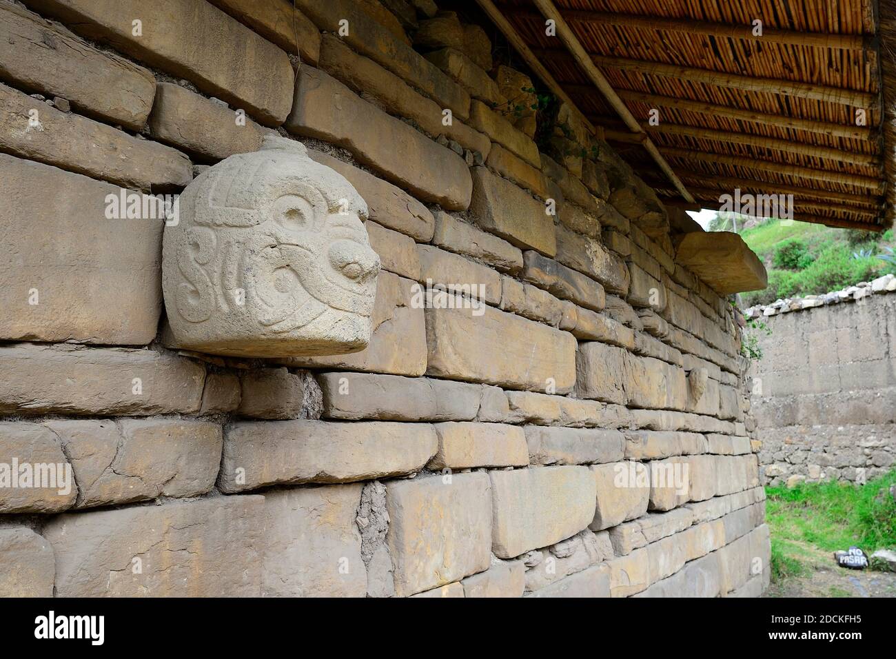 Stone head, half man half cat, on a wall of the ruins of Chavin de ...