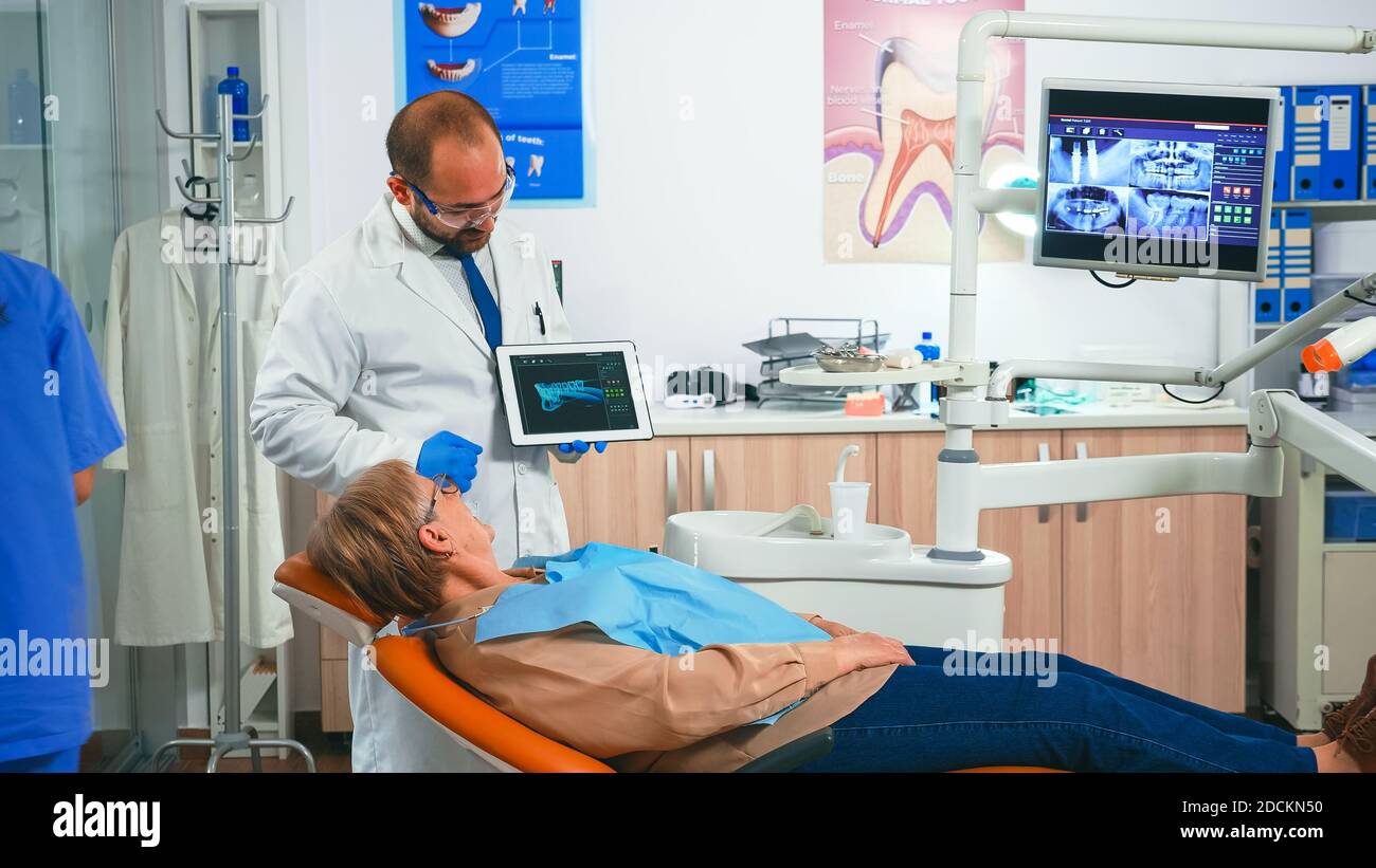 Woman sitting on stomatological chair listening doctor looking on ...