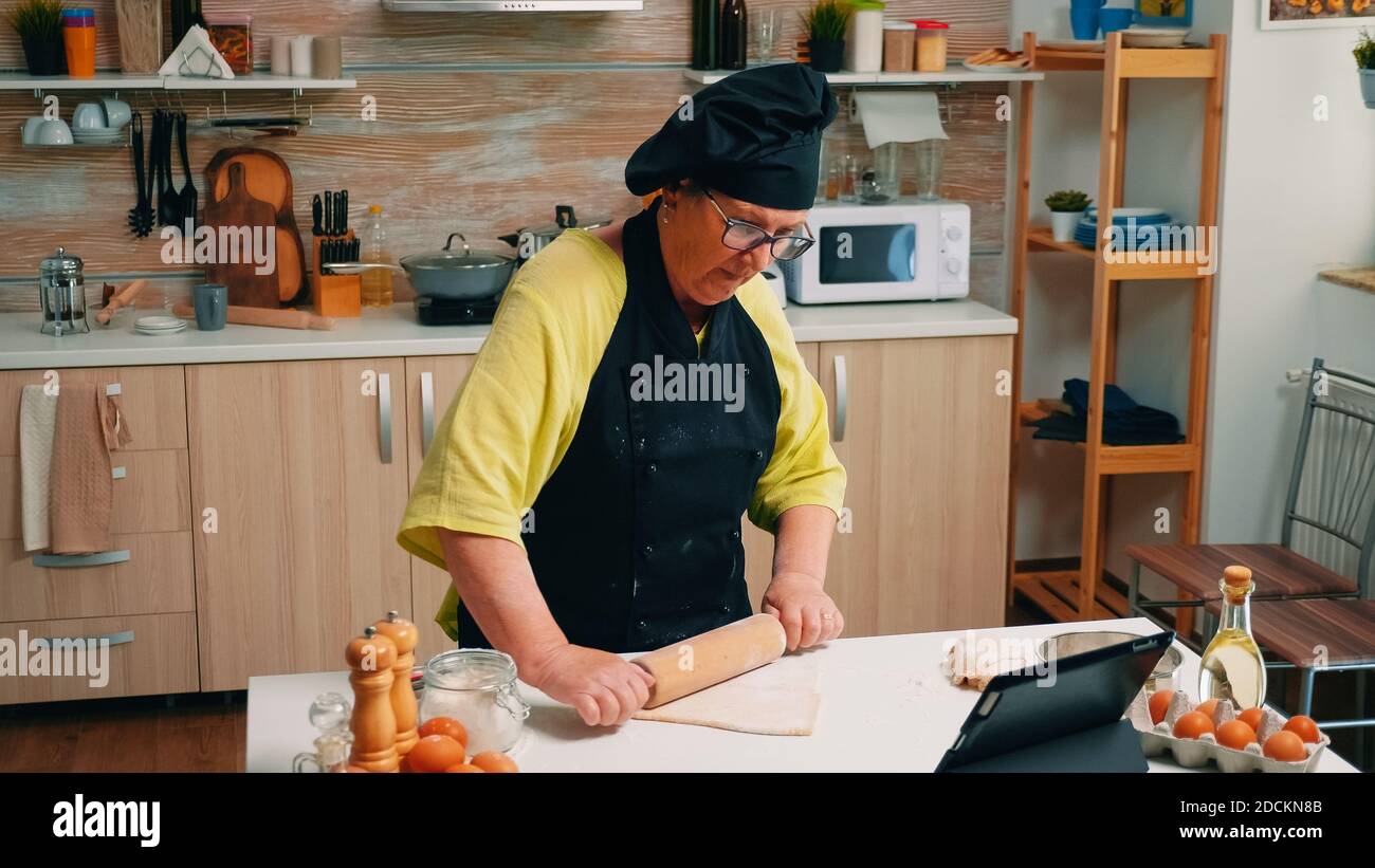 Senior woman with bonete looking recipe at the digital laptop. Retired ...