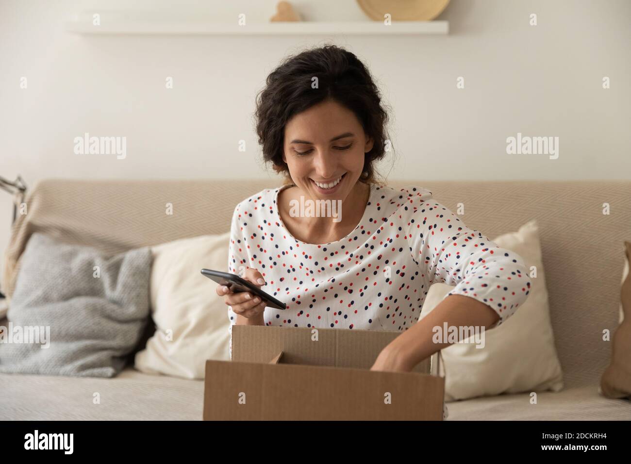 Smiling Caucasian woman unpack box with internet order Stock Photo - Alamy