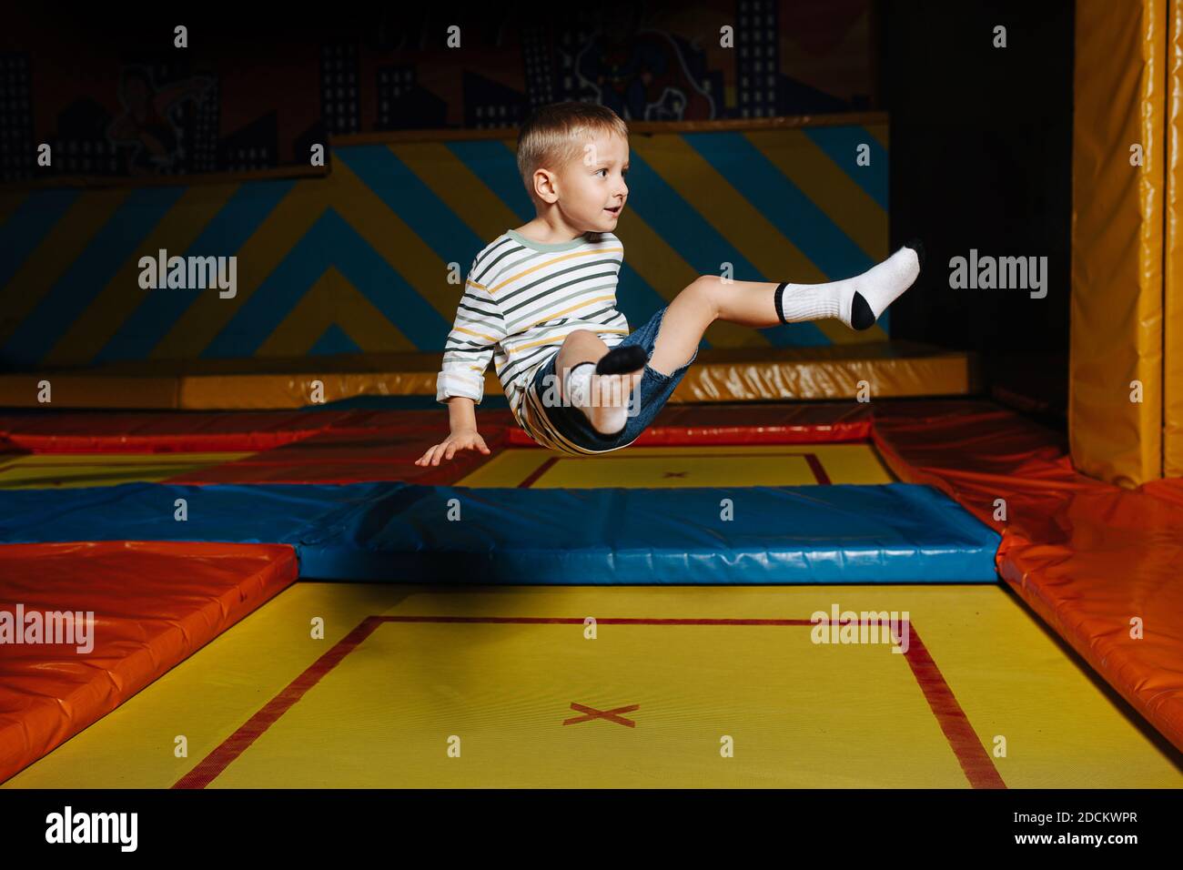 Little boy jumping high on a square trampoline in entertainment center ...
