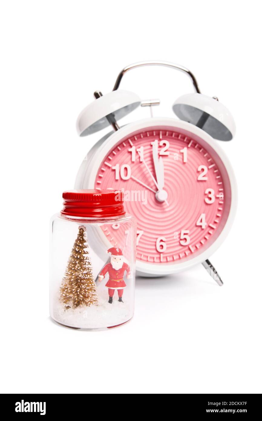 Festive alarm clock showing a minute before midnight next to a ...