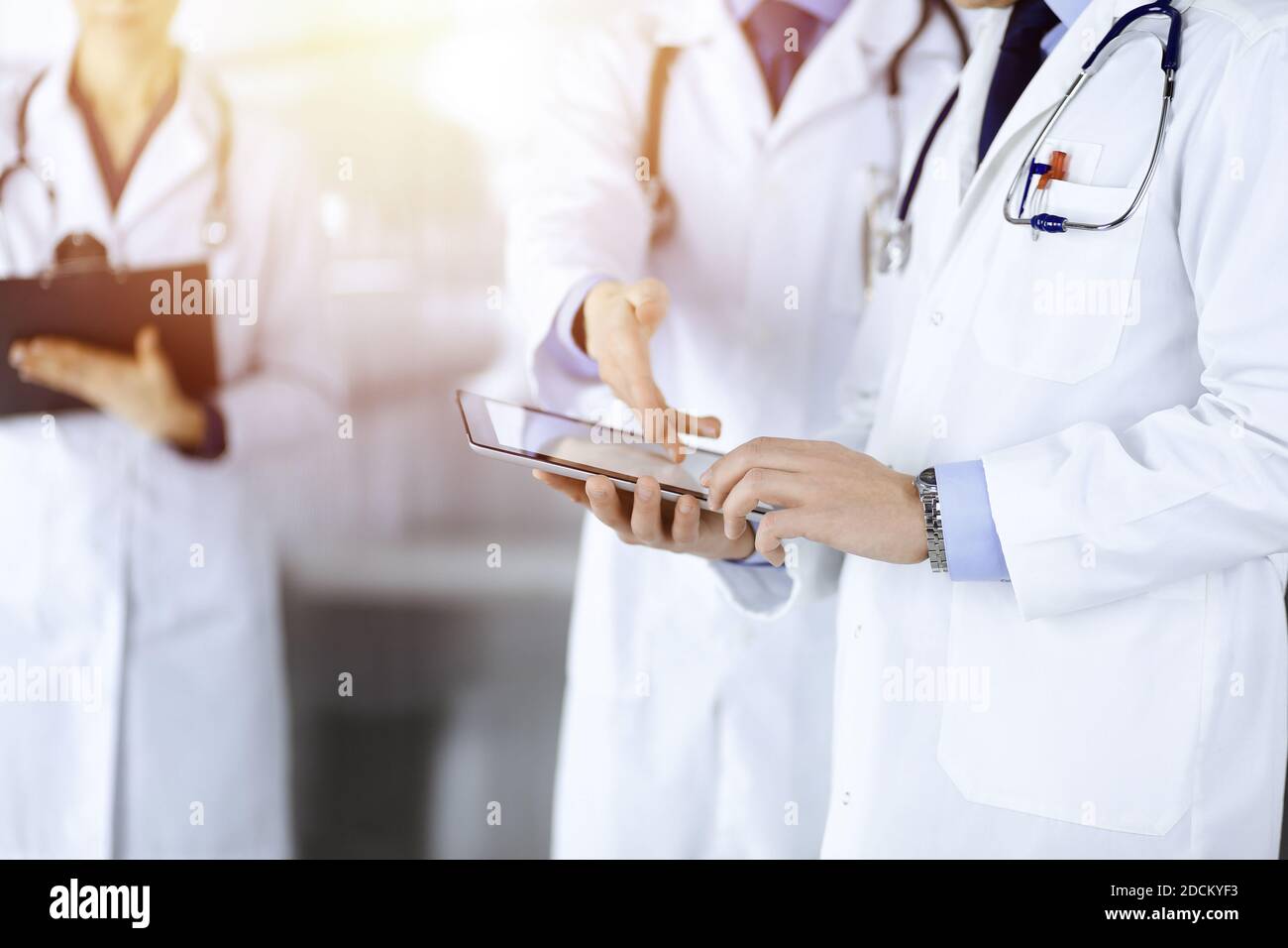Group of unknown doctors use a computer tablet to check up some medical ...