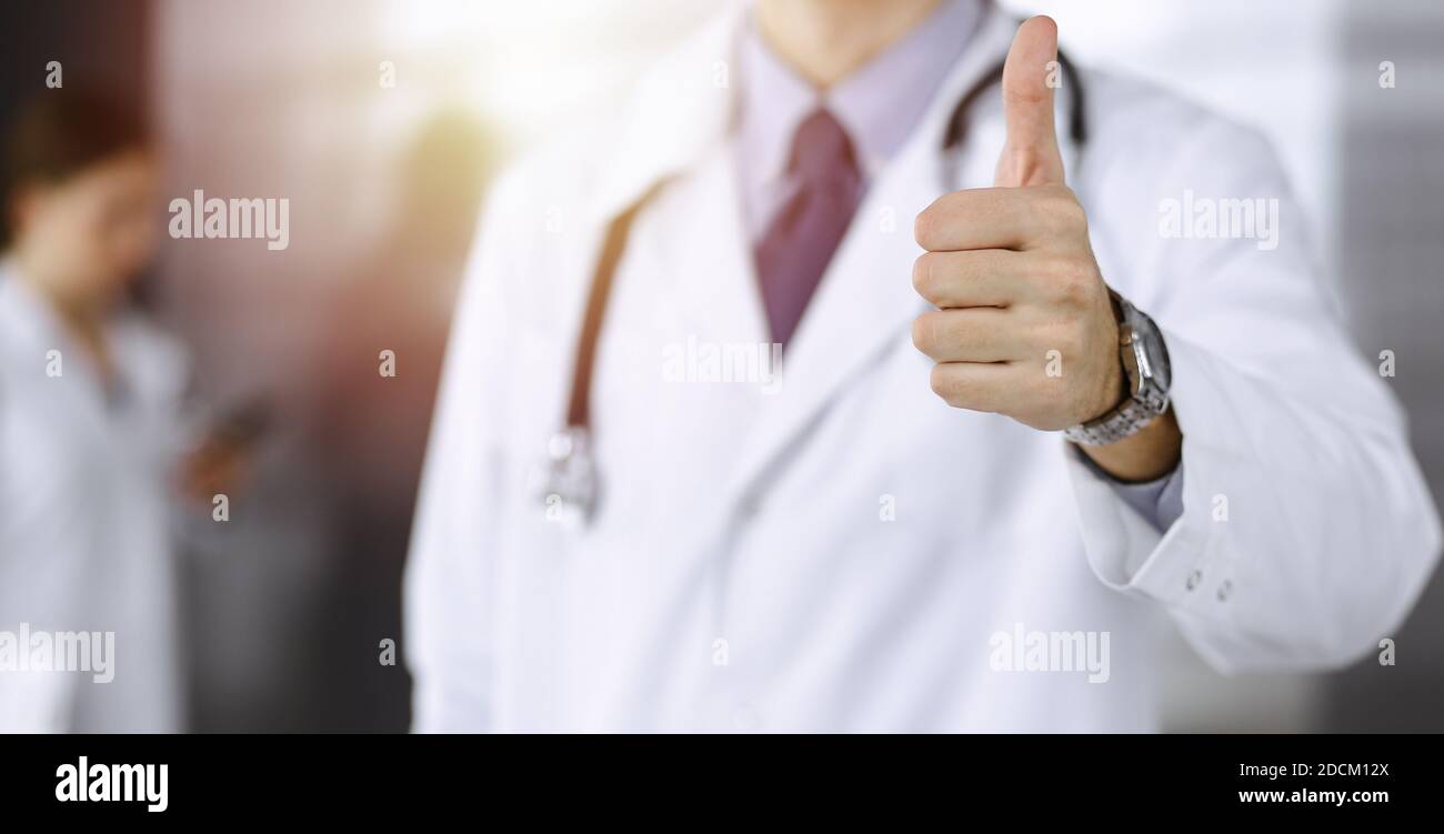 Unknown man-doctor standing straight and showing Ok sign with thumb up ...