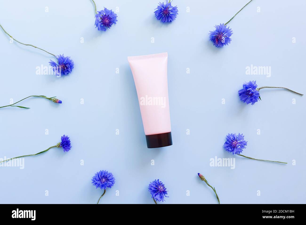 Mockup of pink squeeze cosmetic tube with black cap and blue flowers ...