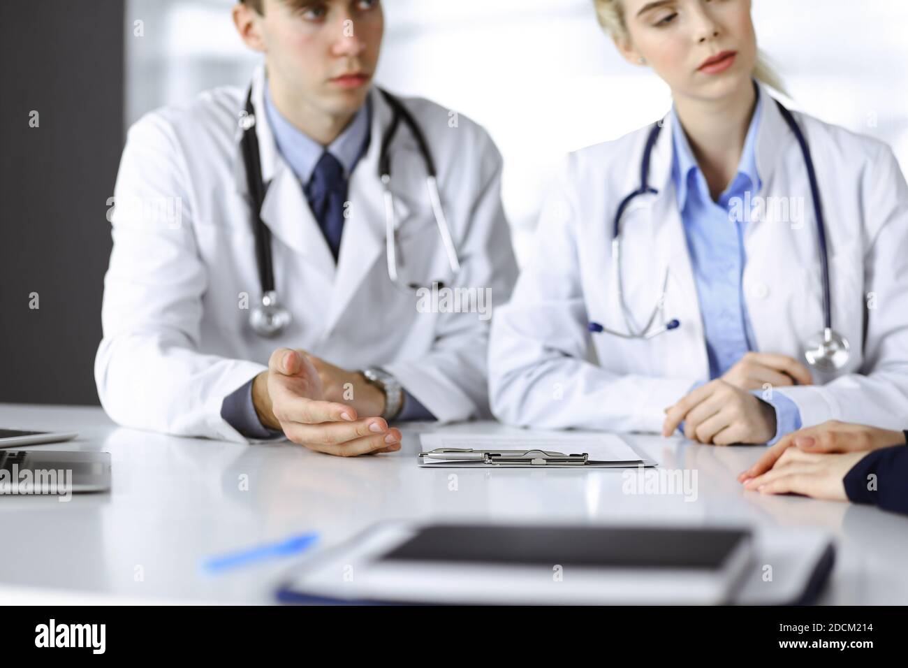 Two doctors and patient woman discussing something while sitting at the ...