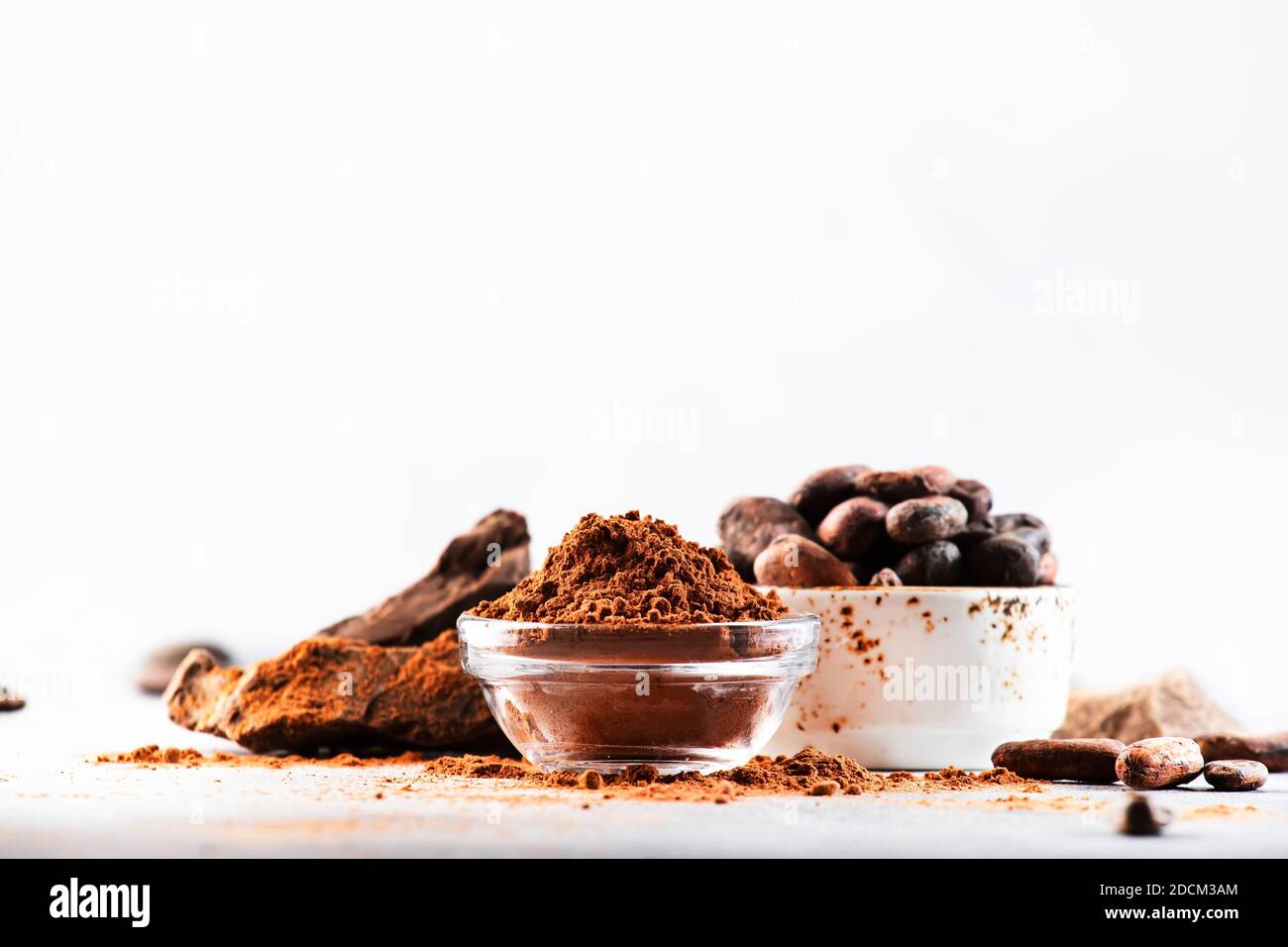 Organic cocoa powder, cocoa beans, grated cocoa lump on gray background ...