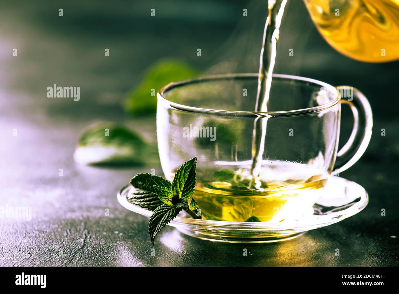 Hot chinese green tea with mint, with splash pouring from the kettle ...