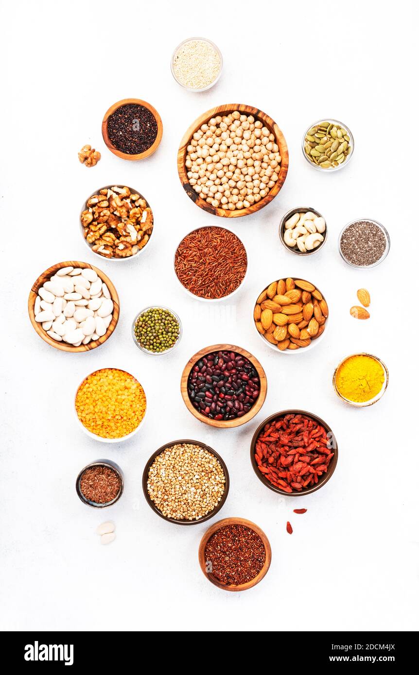 Various superfoods, legumes, cereals, nuts, seeds in bowls on white ...