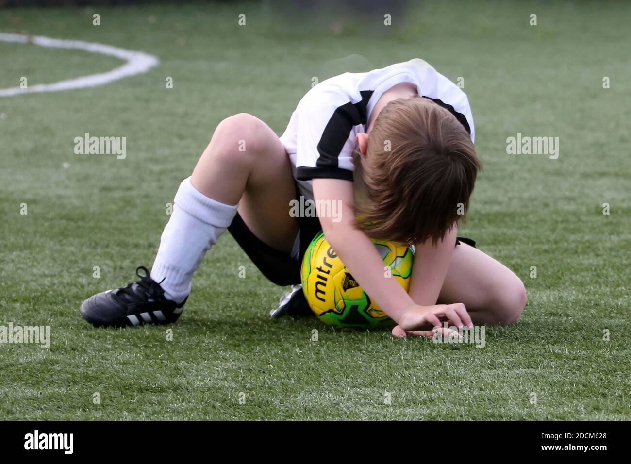 A young boy cradles a football after letting in a goal, feeling ...