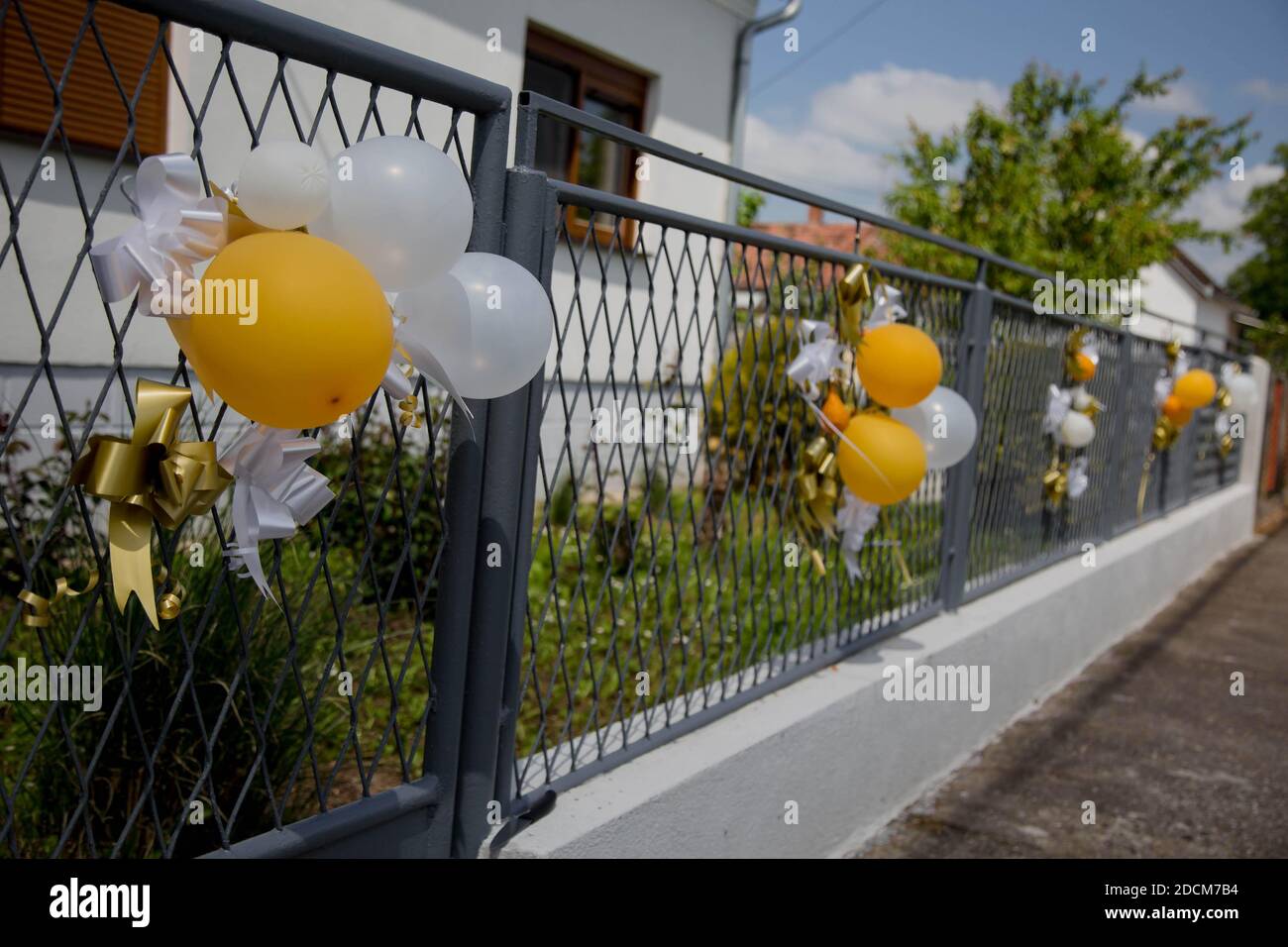A view of white and yellow balloons on the metal fence Stock Photo - Alamy
