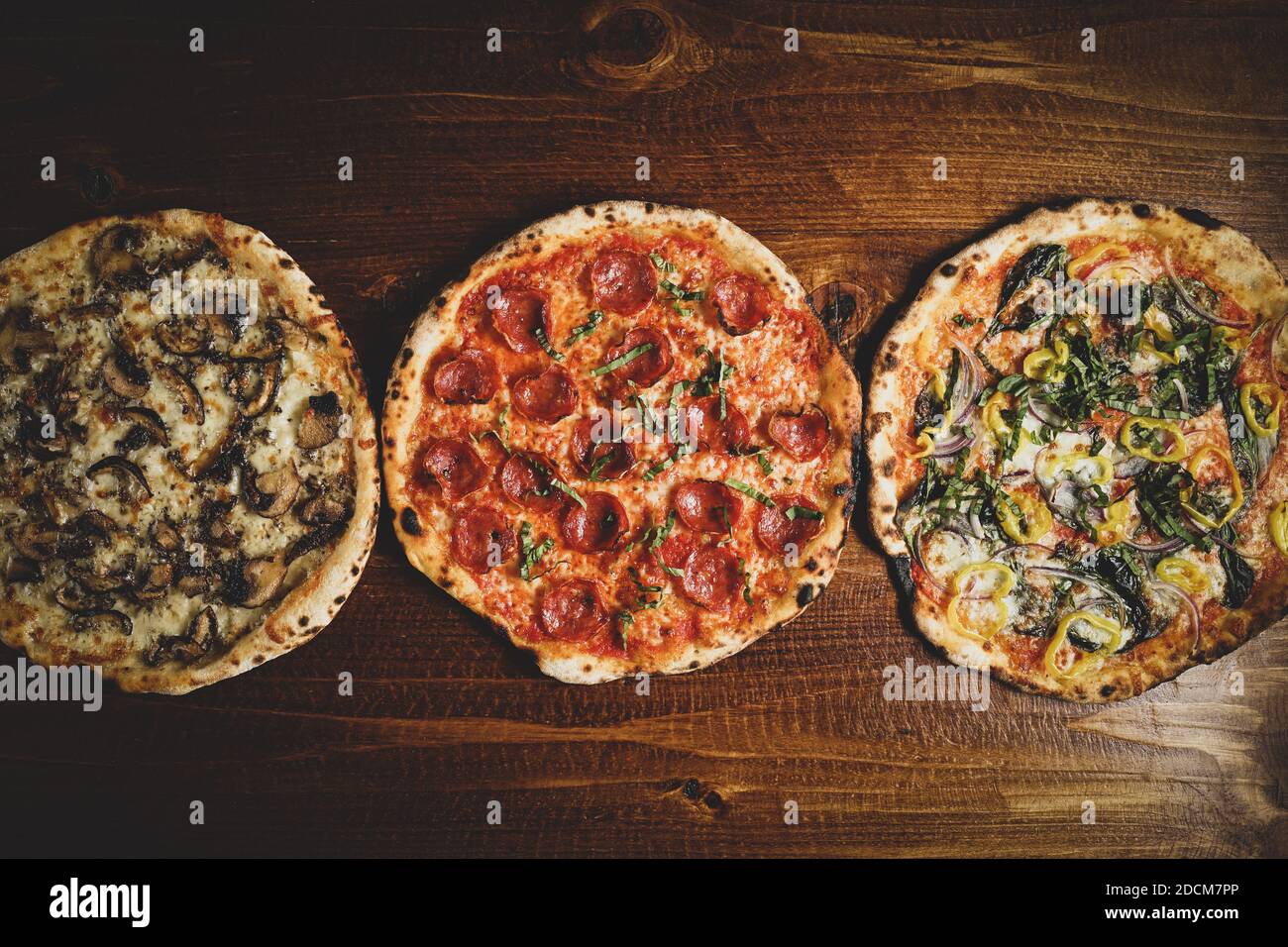 Three pizzas on a wooden board Stock Photo - Alamy