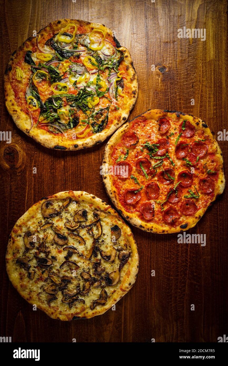 Three pizzas on a wooden board Stock Photo - Alamy