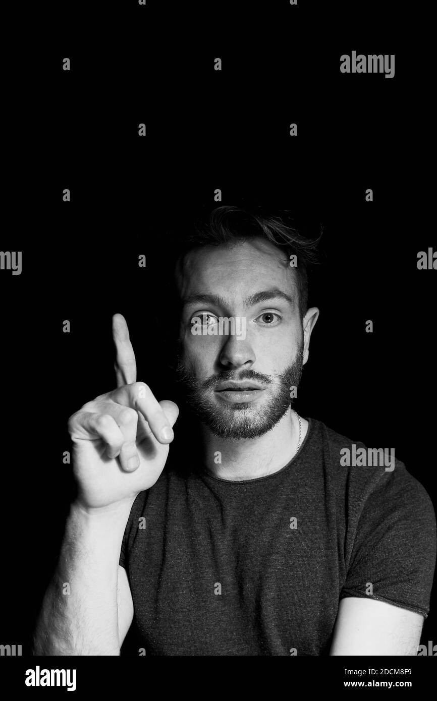 A man on a black background holds his second finger up. The symbol that ...